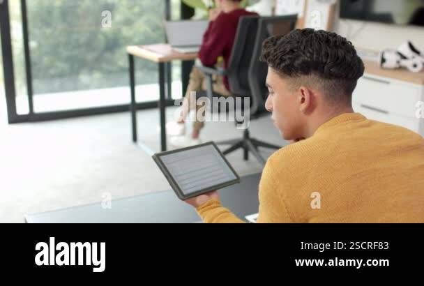 Using tablet, man working from home while partner working on laptop ...