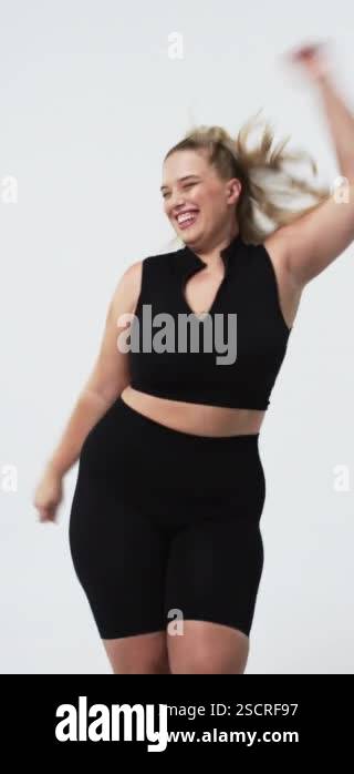 Vertical video: Smiling plus size woman in activewear celebrating body ...