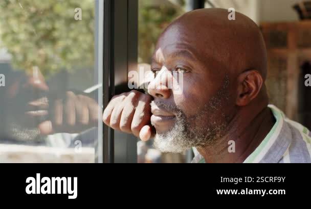 Looking out window, pensive African American man reflecting and ...
