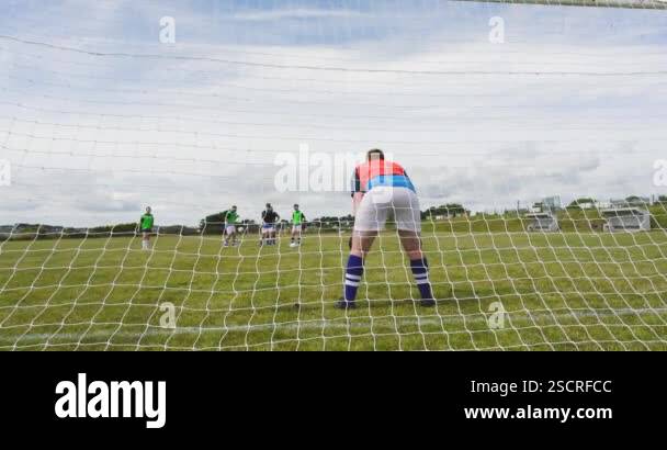 Male and female soccer players playing soccer, shooting at goal with ...