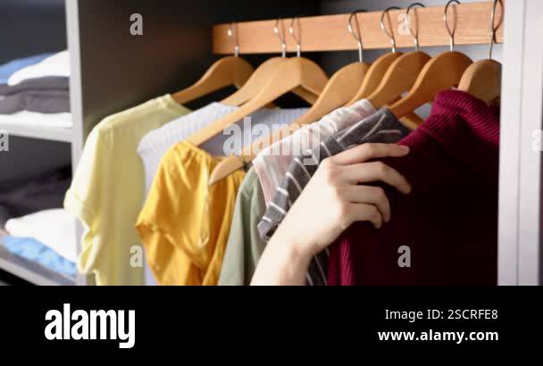 Selecting clothes from wardrobe, person organizing colorful outfits on ...