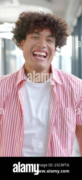Vertical video: Smiling young man wearing striped shirt standing in ...