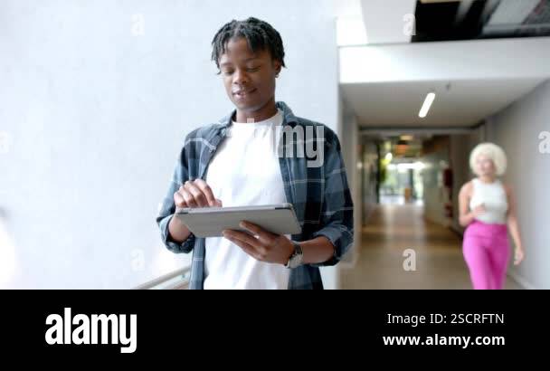 Using tablet, person walking in modern office hallway, focusing on work ...