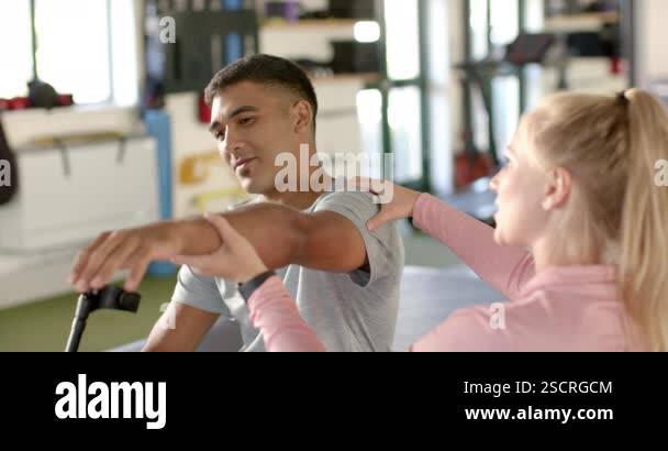 Man in disability rehab exercising arm with assistance from female ...