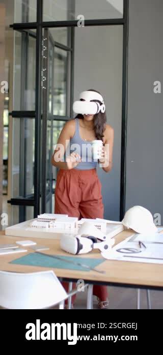 Vertical video: Using VR headset, woman exploring architectural models ...