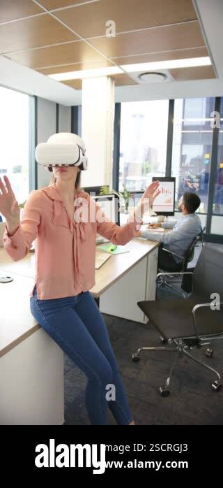 Vertical video: Using VR headset, woman standing by desk while man ...