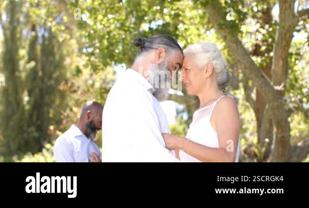 Embracing at outdoor wedding, senior bride and groom smiling with ...