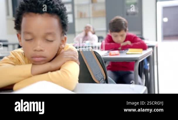 In school, children sitting at desks in the classroom, looking bored ...