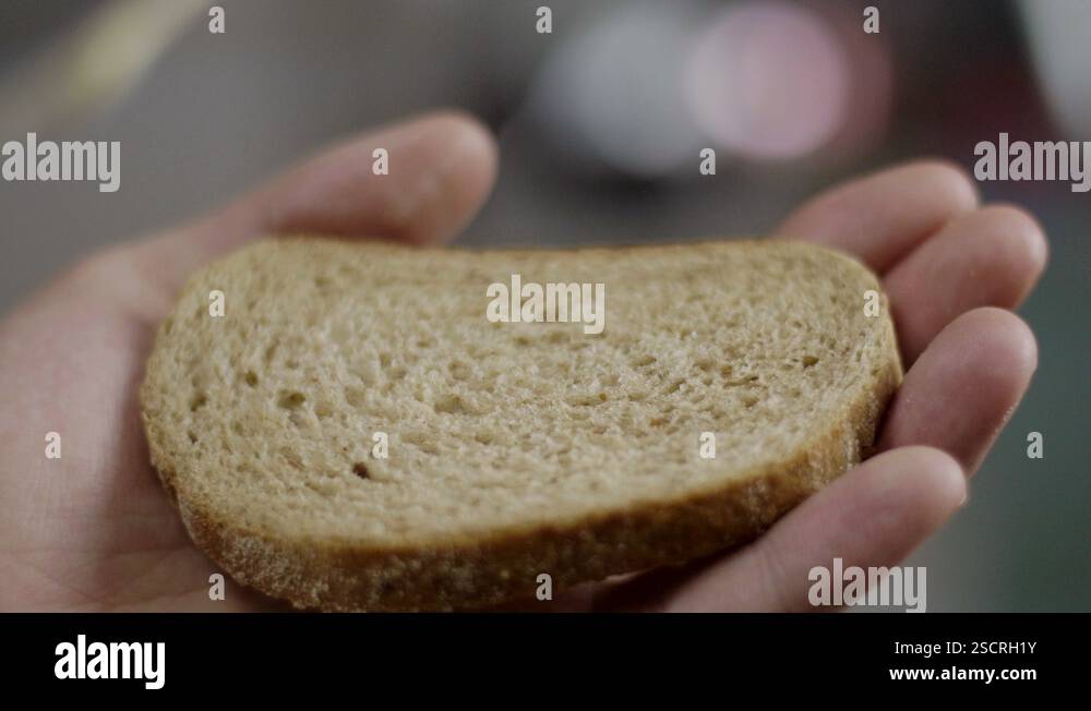 Closeup of male hands slowly spreading butter on ban brown bread in ...