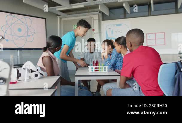 Discussing science project, group of students in school classroom, smiling and engaged ...