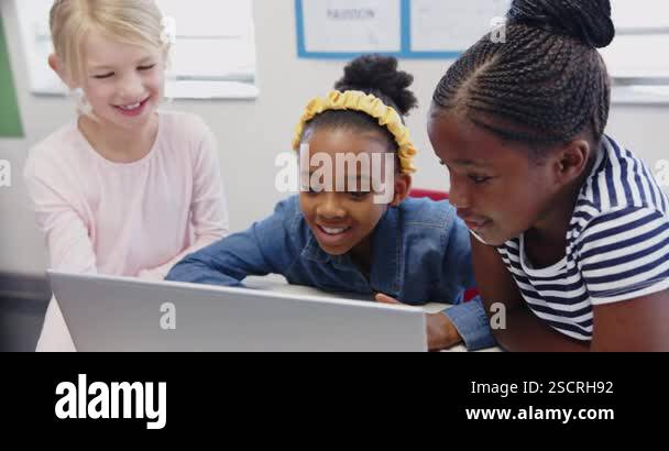 In school, three girls using laptop together, collaborating on project. Education, teamwork ...