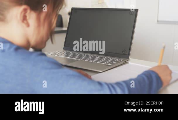 Using laptop and writing in notebook, student studying in school ...