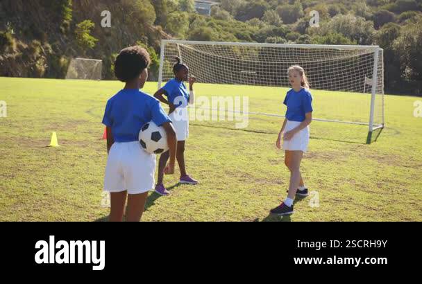 Playing soccer, three school girls in uniform standing on field with ...
