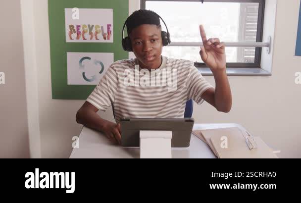 Using tablet and wearing headphones, student studying in school ...
