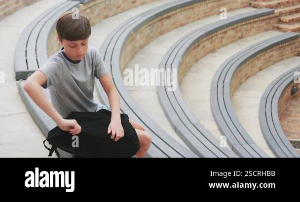 Sitting on steps, boy looking into backpack, preparing for school ...