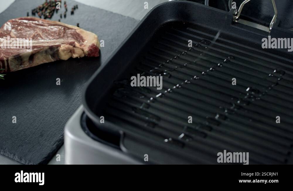 Chef starting to cook meat at griddle. Closeup hands putting greenery ...