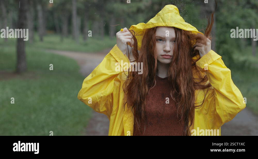 girl walking in the park in the rain throws the hood of a jacket over ...