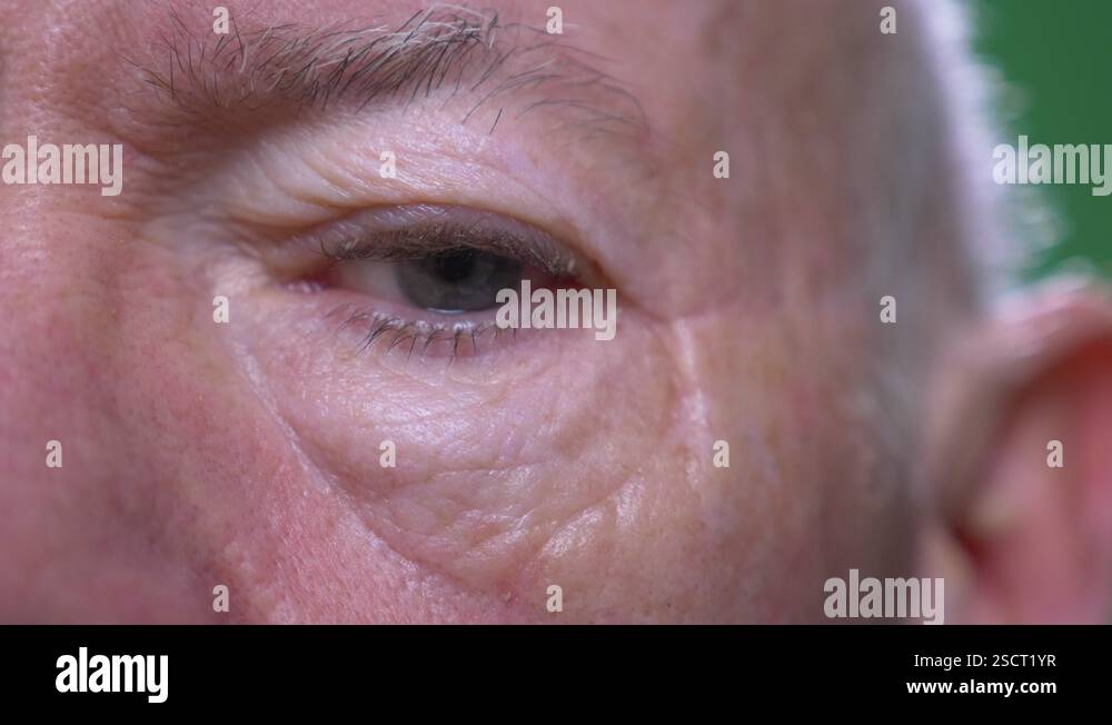 Closeup half face shoot of old senior caucasian male looking at camera ...