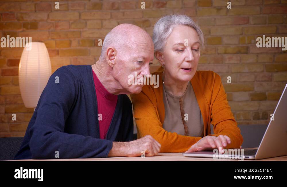 Two progressive senior gray-haired caucasian spouses watching into ...