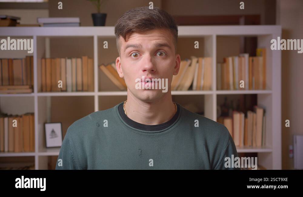 Portrait of young male student shows strong amusement into camera in ...