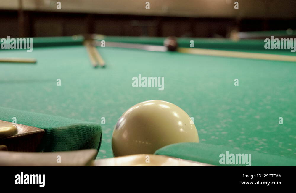 Game. Billiards. Ball rolling down two cues, hitting white ball into ...