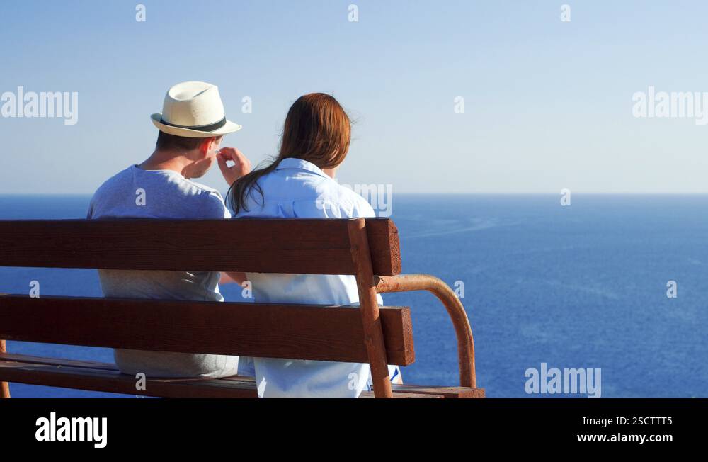 Young couple in love relax on bench near sea listening music with ...
