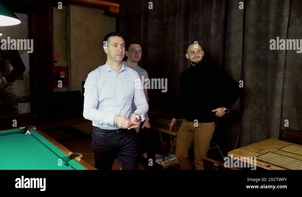 Men playing in game of darts, throwing a dart arrow in center of ...