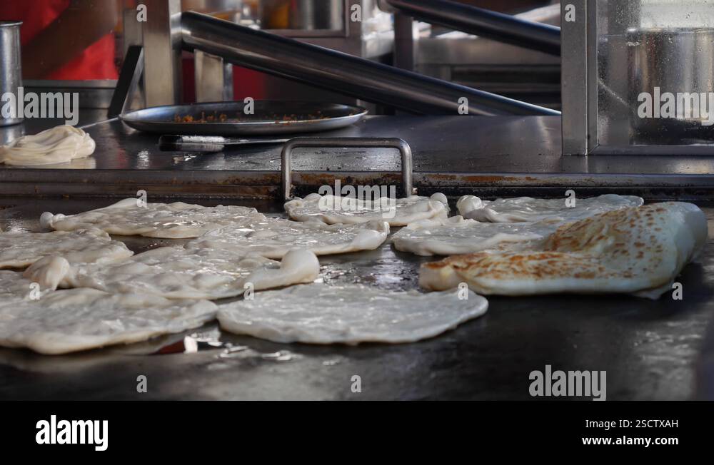 Chef making a lot of traditional Indian food called 'Roti Canai'. 4k ...