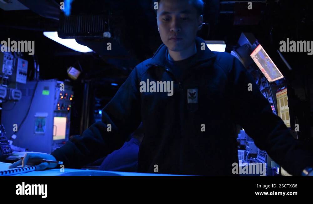 Sailor reading from navigation chart in control room aboard USS Mount ...