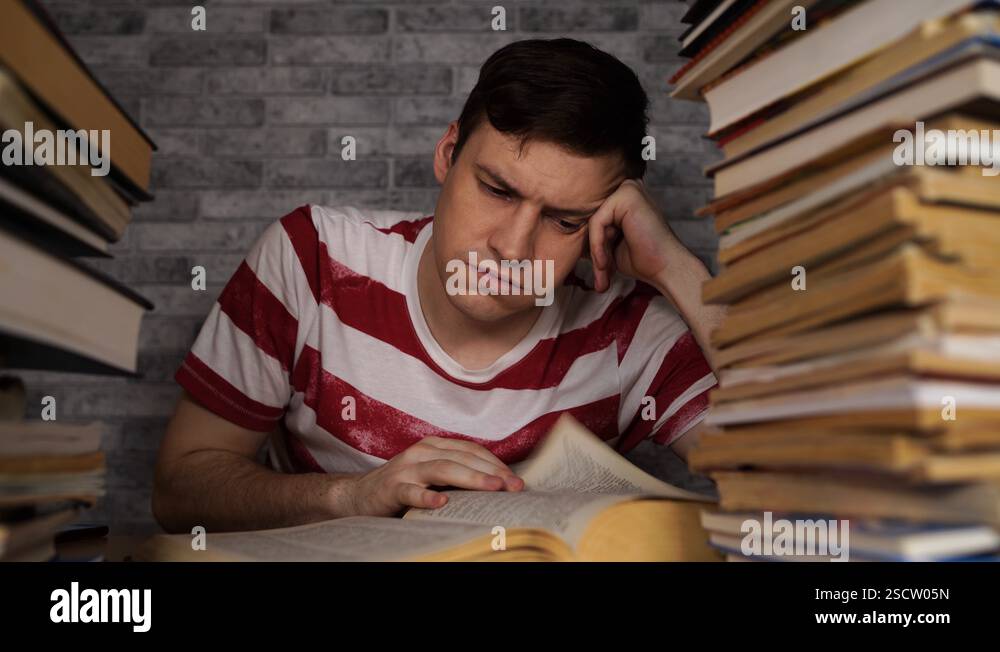 Man student boring reading book at library with a lot of books in ...