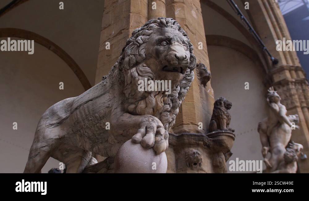An ancient statue of a stone marble lion that holds a paw on a small ...