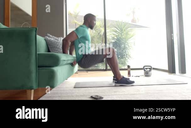 Strong and fit man doing tricep dips using sofa at home, exercising ...