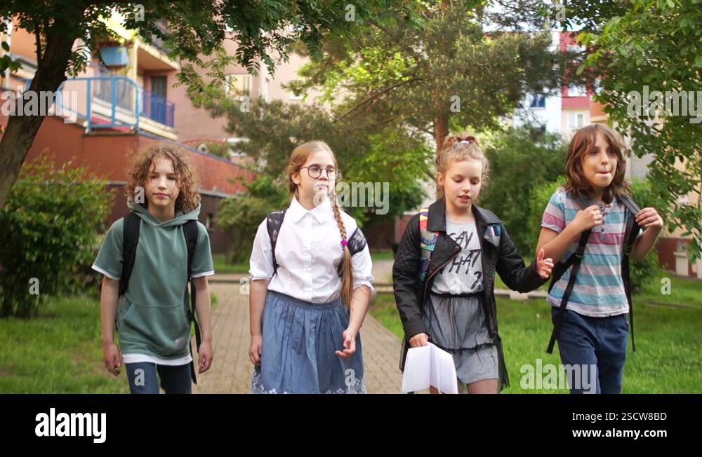 Children go from school, front view. The girl throws up sheets of paper ...