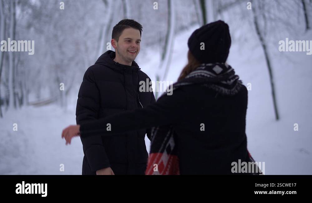Pretty young woman runs up to the guy and jumps into his arms in winter ...