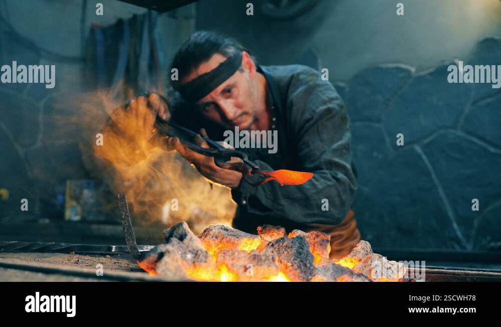 Metal element is being held above the fire by the blacksmith Stock ...