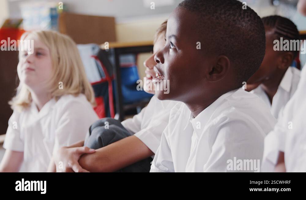 Group Of Elementary School Pupils Wearing Uniform Sitting On Floor ...