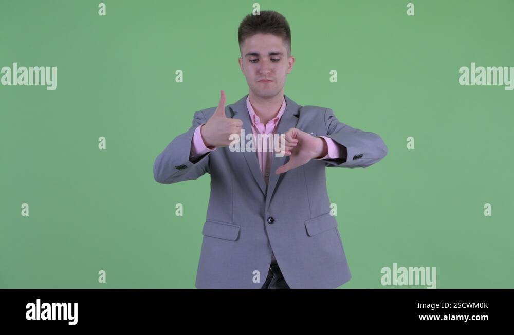 Confused young businessman choosing between thumbs up and thumbs down ...