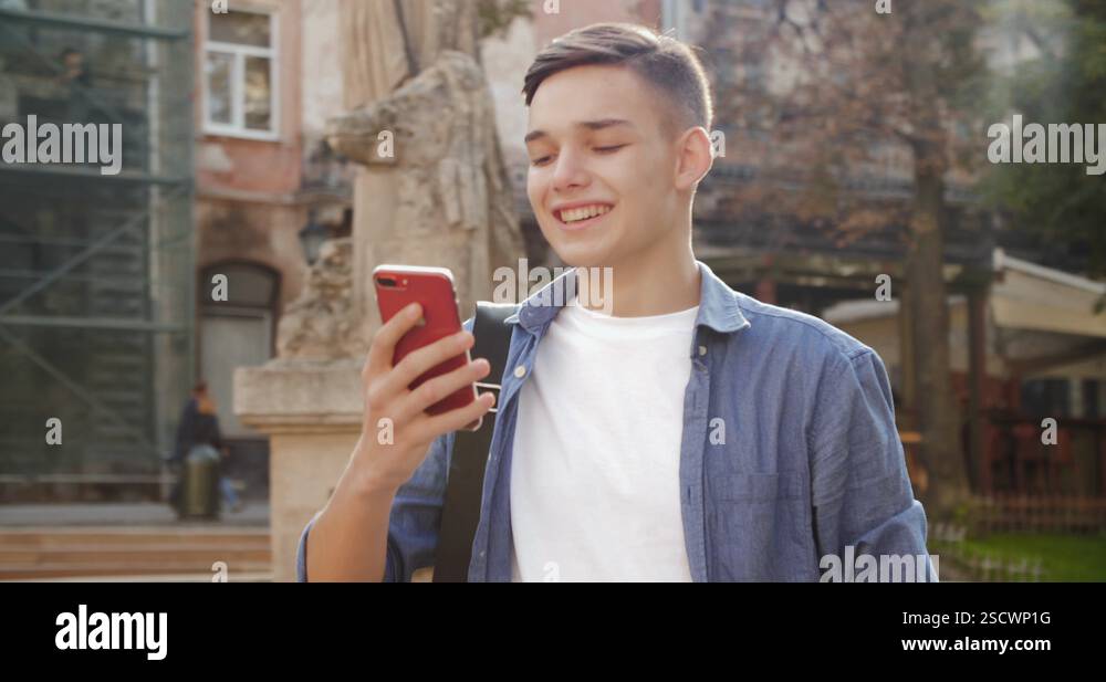Young Attractive Boy smiles charmingly while Texting Message on his ...
