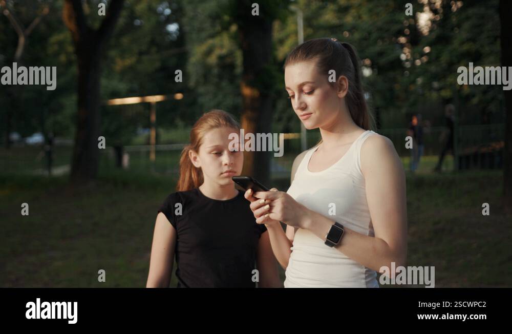 Nice-looking beauty fit sisters spend time in the city park watch ...