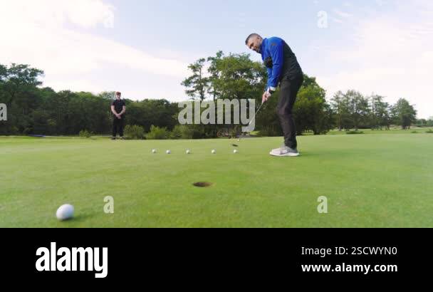 Two male golf players playing golf together, hitting balls with club on ...
