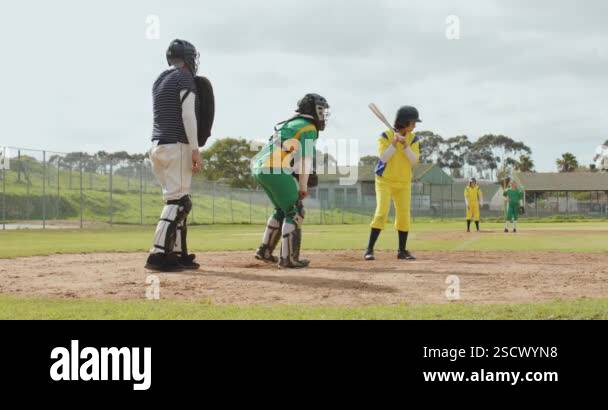 Multiracial female baseball players and male umpire playing baseball, throwing the ball on a ...