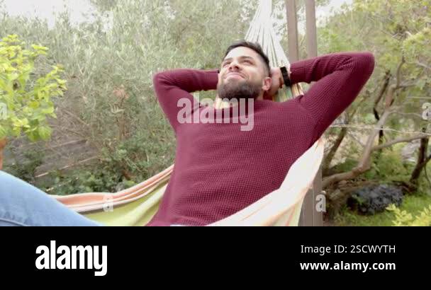 Relaxing in hammock, man enjoying leisure time outdoors in backyard ...
