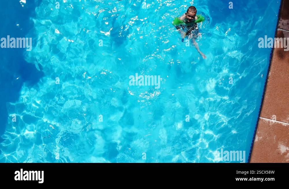 Aerial rising shot of kids playing in a fun swimming pool at a house ...