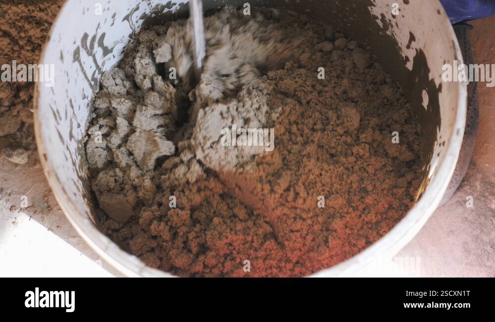 Long drill mixer mixing cement sand and water creating mortar glue ...