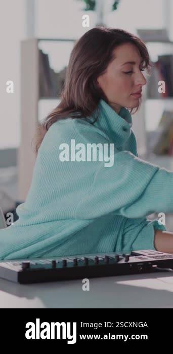 In a focused environment, a woman in a blue sweater works at her desk ...