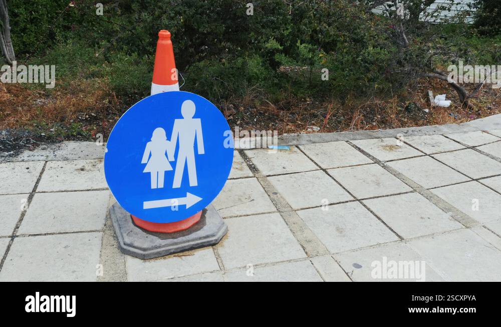 Blue pedestrian direction detour sign on a traffic red cone. Road under ...
