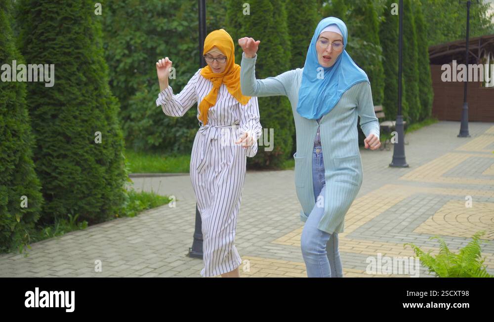 Two positive Muslim young women dancing in the park Stock Video Footage ...
