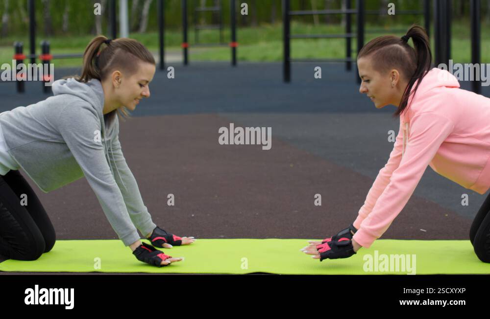 Twin Sisters Doing High-Fives in Plank Posture at Outdoor Gym Stock ...