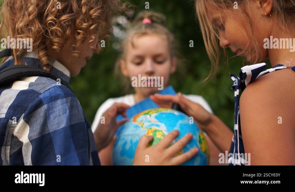 School tasks, three classmates study a large globe, geography lesson ...