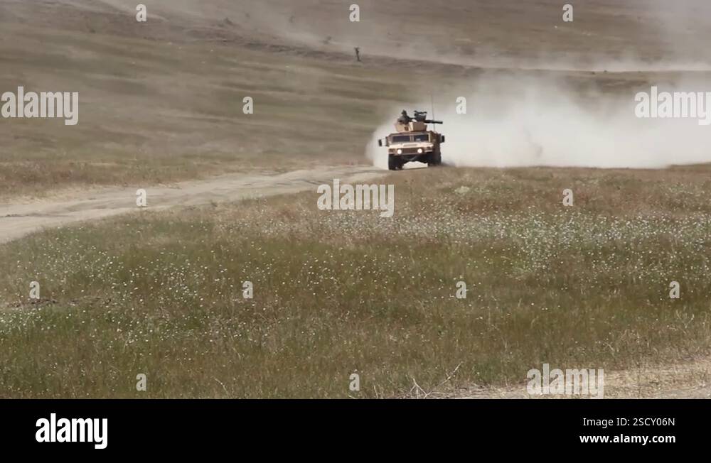 Up-armored Humvee creating dust cloud while travelling at speed along ...